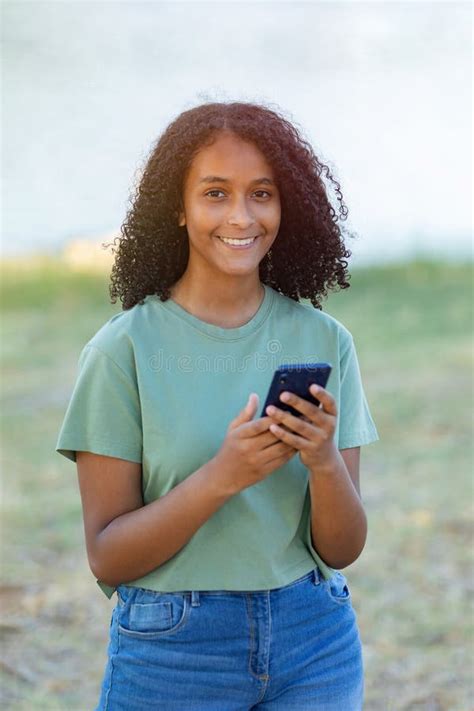 Beautiful Smiling Girl With Curly Hairstyle Using Smart Phone Stock