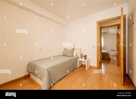 Bedroom With Youthful Bed With Gray Bedspread With Matching Cushions And Oak Wood Flooring Stock