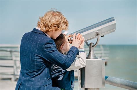 Two Blonde Hair Brothers Looks Together In Binoculars On The Sea Stock