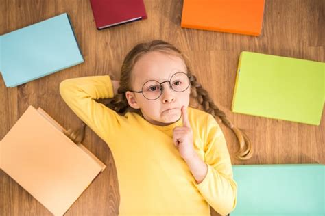Premium Photo Little Pretty Girl In Glasses Laying On Floor With Books