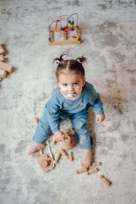 장난감을 가지고 노는 바닥에 앉아 있는 어린 소녀 사진 Unsplash의 아이 이미지