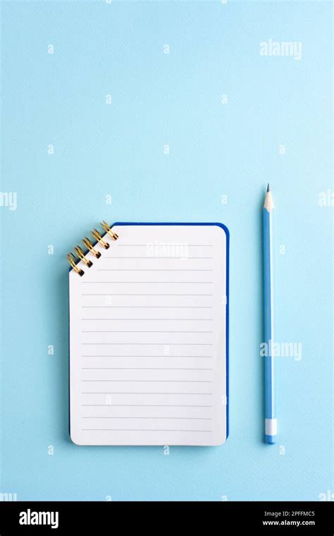 Vertical Background With Note Book Paper Page And Blue Sharp Pencil On
