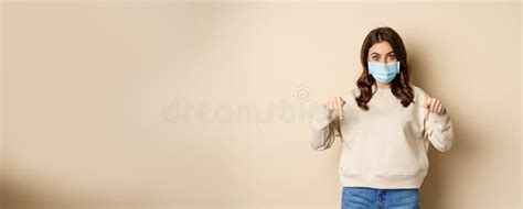Cute Girl In Medical Face Mask Pointing Fingers And Looking Down