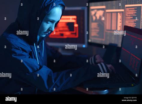 Girl Hacker In A Hood Typing Program Code While Committing A Cybercrime