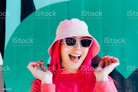 분홍색 머리와 버킷 모자를 쓴 선글라스를 쓴 행복한 감정적인 젊은 여성은 뺨에 꽃 스티커를 붙인다 애니메이션 스타일 여름 봄