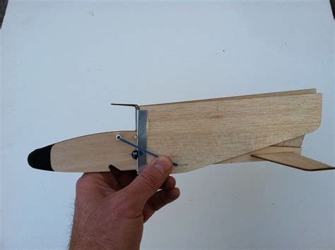 A Hand Holding A Wooden Plane With Metal Blades On Its Side And
