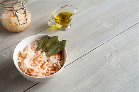 회색 콘크리트 배경에 수제 전채 소금에 절인 양배추흰색 세라믹 그릇 유리 항아리와 격자 무늬는 콜슬로와 당근을 다진 0명에 대한