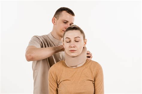신경 외과 의사는 흰색 배경에 목 통증 부상 및 염좌의 경우 자궁 경부를 안정시키기 위해 소녀에게 목 붕대를 감습니다 25 29