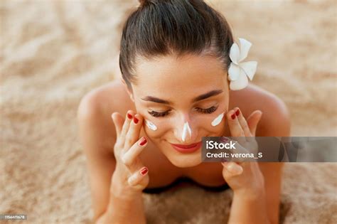 선탠 로션 여성 선스크린 선크림 을 적용 아름다운 행복 한 귀여운 여자 배경에 바다와 그녀의 코에 플라스틱 용기에서 선탠 크림을 적용 개념에 대한 스톡 사진 및 기타 이미지