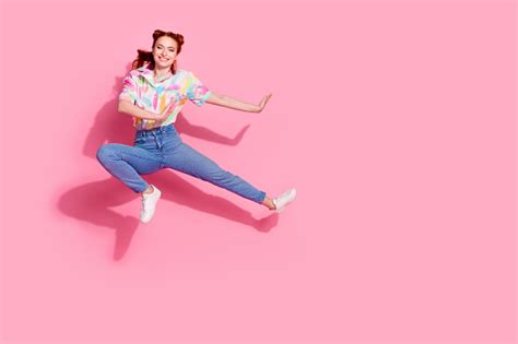 캐주얼 복장 점프 연습 싸움 닌자 킥에 매력적인 빨간 머리 젊은 여자의 전신 길이 사진 분홍색 배경에 고립 된 가라테에 대한