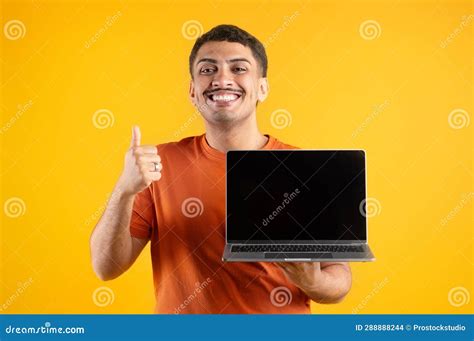 Smiling Brazilian Man Showing Laptop With Blank Screen And Gesturing