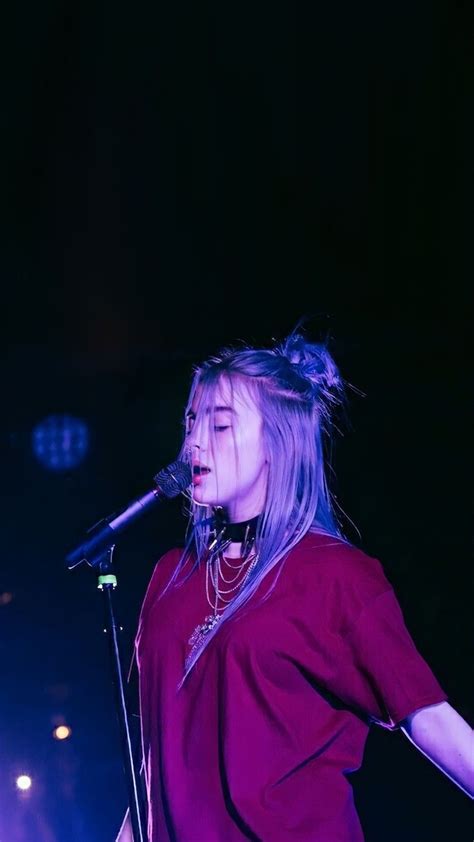 A Woman Standing In Front Of A Microphone On Stage