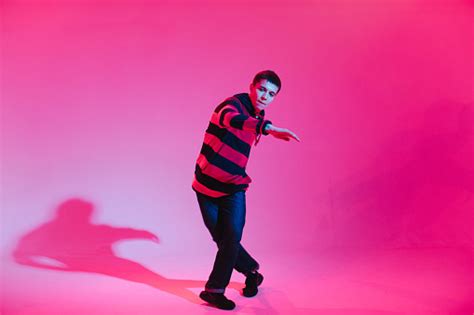 스튜디오에서 점퍼 댄스 현대 무용을 입은 청년 브레이크 댄스 댄스 스쿨 포스터입니다 공간을 복사합니다 전투 대회 발표 분홍색과 파란색 배경입니다 공연에 대한 스톡 사진 및