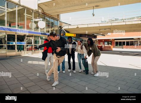 Multiracial Friends Cheering Male Friend Dancing On Street In City