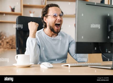 Image Of Laughing Programmer Man Making Winner Gesture While Working