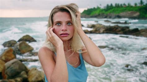 Woman In Blue Dress Stands On Beach Cliff At Stormy Sea Blonde Hair