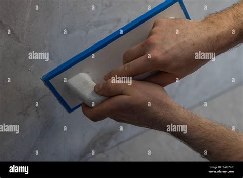 Worker Applying Grout On Ceramic Tiles Using A Rubber Float During Wall