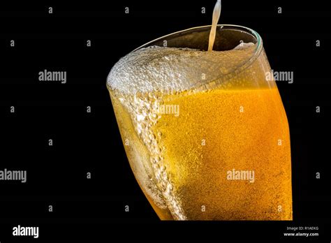 Stream Of Beer Being Pouring Into A Glass With Beer And Foam Isolated
