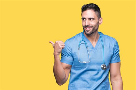 생기고 엄지 측면 가리키는 행복 한 얼굴로 웃 고 고립 된 배경 위에 잘생긴 젊은 의사 외과 의사 남자 의사에 대한 스톡 사진 및 기타 이미지 Istock