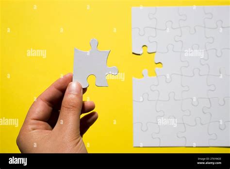 Person S Hand Holding Missing White Jigsaw Puzzle Piece Yellow Backdrop