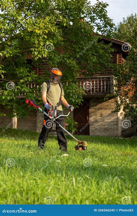 Side View Of A Gardener With Electrical String Grass Cutter Trimming