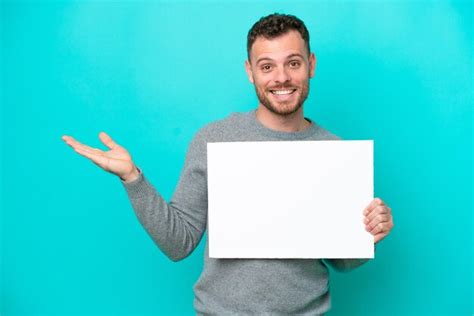 Joven brasileño sosteniendo un cartel vacío aislado de fondo azul sosteniendo un cartel vacío