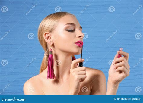 Beautiful Young Woman Applying Bright Pink Lipstick On Color Background