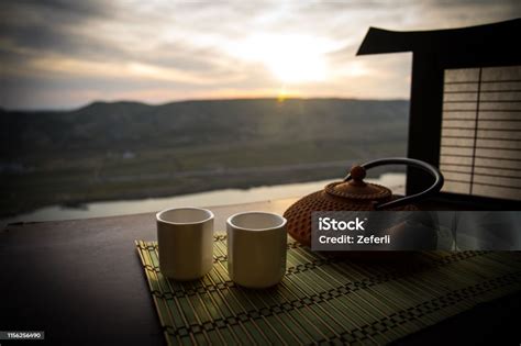 차 개념입니다 일본 다도 문화 동쪽 음료 석양을 바라보며 대나무 잎을 곁들인 테이블 위의 찻주전자와 컵 0명에 대한 스톡 사진