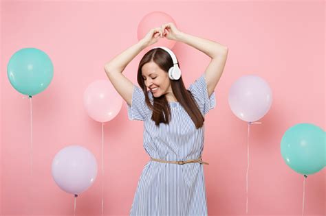 파란 드레스 듣기 음악 화려한 공기 풍선 파스텔 핑크 배경에 춤 헤드폰 웃는 매력적인 젊은 여자의 초상화 생일 휴가 파티 사람들이 진심으 감정 14에 대한 스톡 사진 및