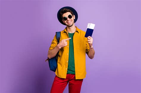 벨벳 모자 배낭 홀드 티켓 공기 비행 포인트 집게 손가락 조언 퍼스트 클래스 착용 노란색 셔츠 빨간 바지 바지 고립 된 보라색