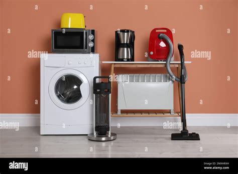 Set Of Different Home Appliances With Vacuum Cleaner Near Brown Wall