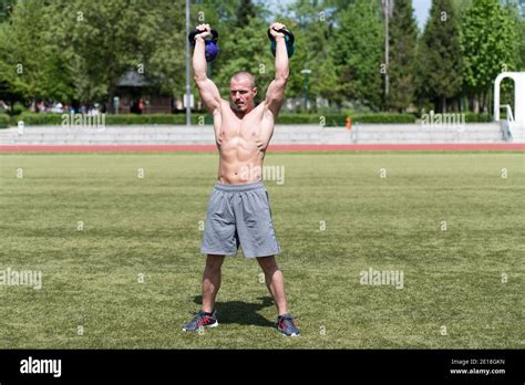 Man Exercising With Kettle Bell Outdoor And Flexing Muscles Muscular