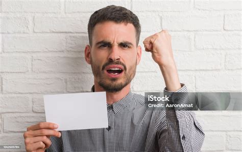 벽돌 벽 잡고 빈 종이 화가 위에 젊은 성인 남자와 미친과 제기 손으로 소리 분노와 좌절 외치고 분노 개념 간판에 대한 스톡 사진 및 기타 이미지 Istock
