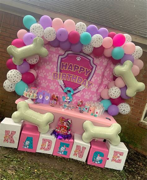 A Birthday Cake Table With Balloons And Dog Bone Decorations On The Top
