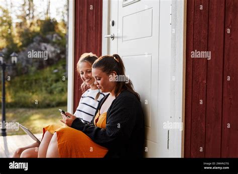 Female Friends In Front Of Wooden House Stock Photo Alamy