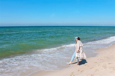 Premium Photo A Girl Walks Along The Shore Of The Blue Sea On The