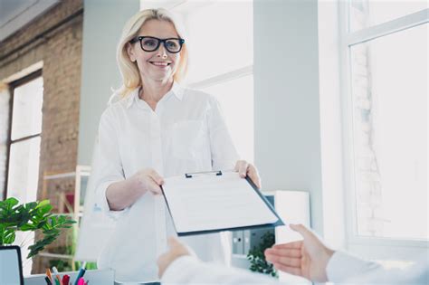 사무실에서 정장 흰 셔츠와 안경을 쓴 금발의 비서 여성이 서명을 요구하는 문서를 들고 있는 사진 45 49세에 대한 스톡 사진 및 기타 이미지 Istock
