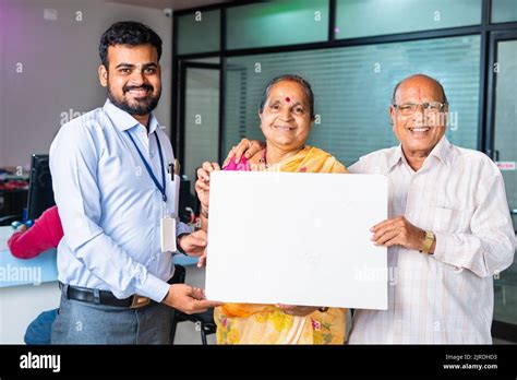 Happy Smiling Banker With Senior Couple Showing White Empty Board By