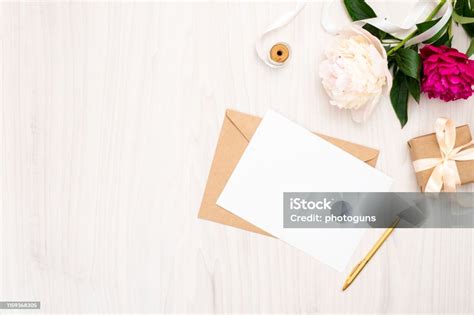 나무 배경에 플랫 누워 모란 꽃 공예 봉투 빈 종이 카드 선물 상자 펜 리본 탑 뷰 여성 스러운 작업 공간 결혼식 초대 카드 모형 부드러운 최소한의 구성 인사장에 대한 스톡