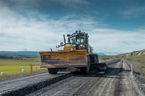 아이슬란드의 그레이저 채점 또는 프로파일링 자갈 길 아스팔트로 포장되지 않은 전형적인 아이슬란드 도로의 일상적인 유지 보수 아이슬란드의 화창한 날 0명에 대한 스톡 사진 및