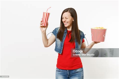 닫힌 눈 영화 영화를 보고 팝콘의 버켓과 소 다 또는 콜라 흰색 배경에 고립의 플라스틱 컵을 들고 젊은 웃는 매력적인 여자의
