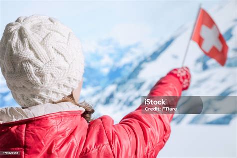 눈 덮인 산을 배경으로 한 겨울 니트 화이트 캡 빨간 재킷을 입은 젊은 여성의 뒷모습 마운트 의 상단에 스위스 플래그와 소녀 겨울에 대한 스톡 사진 및 기타 이미지 Istock