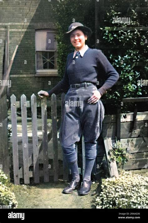 A Member Of The Womens Land Army Land Girl During The Second World War Standing By A Garden