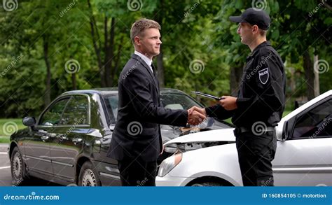 Businessman And Policeman Shaking Hands Car Accident Scene Collision