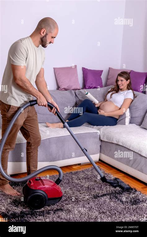 Young Husband Doing House Chores He Is Vacuuming The Living Room While