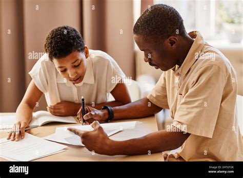 Side View Portrait Of Male African American Tutor Working With Teenage Girl Preparing For School