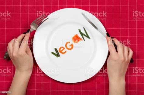 붉은 식탁보 배경에 야채 조각 단어 채식주의와 흰색 접시에 의하여 이루어져 있다 빈티지 포크와 나이프 여성 손입니다 플랫이 하다