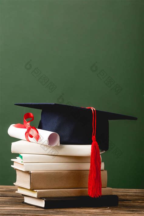 书籍学术帽和文凭的木制表面隔离在绿色 包图企业站