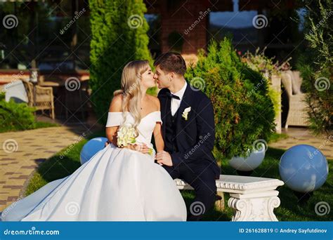 El Novio Y La Novia Vestidos De Forma Tradicional Se Sientan En Un Banco Del Parque Imagen De