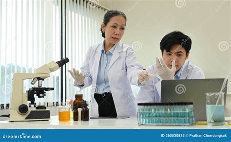 Professional Scientists Using Laptop Computer Collecting Data And Summarising Information For